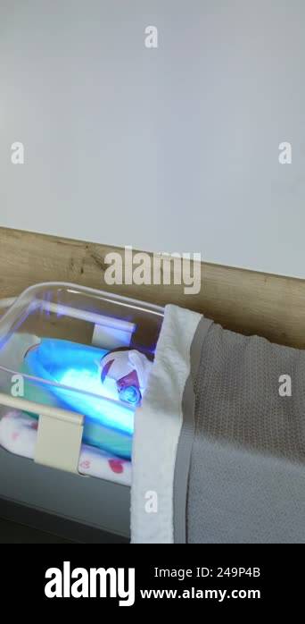 Transparent baby crib with a child in it lying on UV lamp. Infant is ...