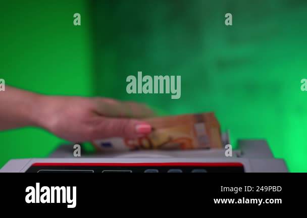 Female cashier's hand places money into cash counting machine. Fifty ...