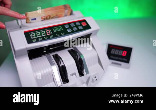 Female hand puts money stack into cash counting machine and its blades ...