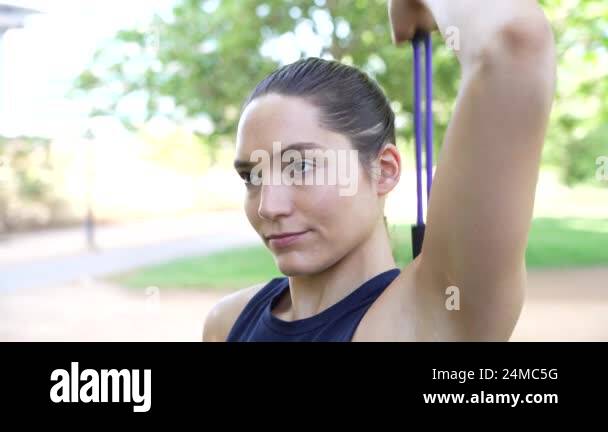 A Young Woman Exercises With A Resistance Band In A Park Promoting A