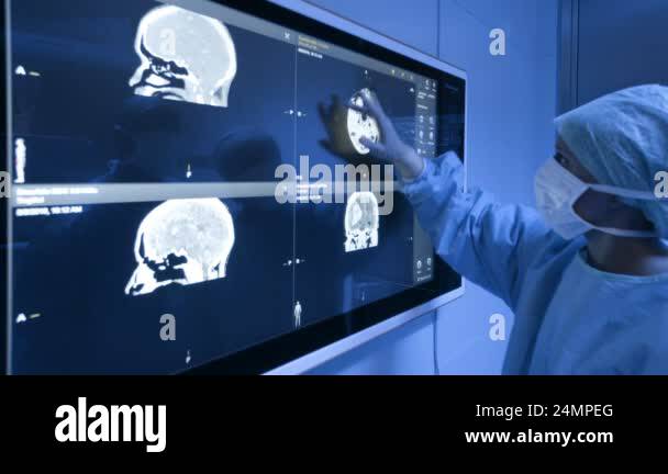 Neurosurgeon using touchscreen monitor in operating room to examine MRI ...