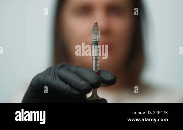 A woman doctor holds a syringe in her hands to give an injection ...