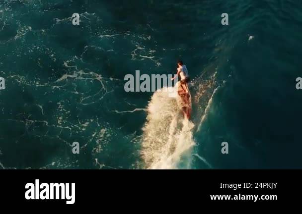 Man surfs the wave. Aerial top down view of the male surfer riding the wave in the Maldives and ...