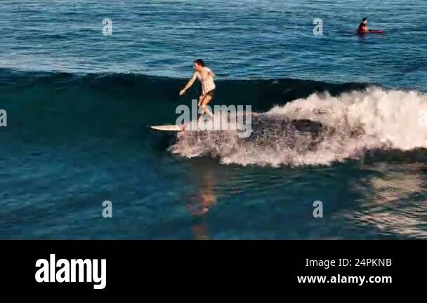 Man surfs the wave and does hand five trick by walking to the nose of ...