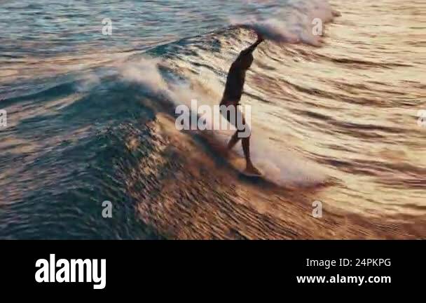 Man surfs the wave and does hand five trick by walking to the nose of ...
