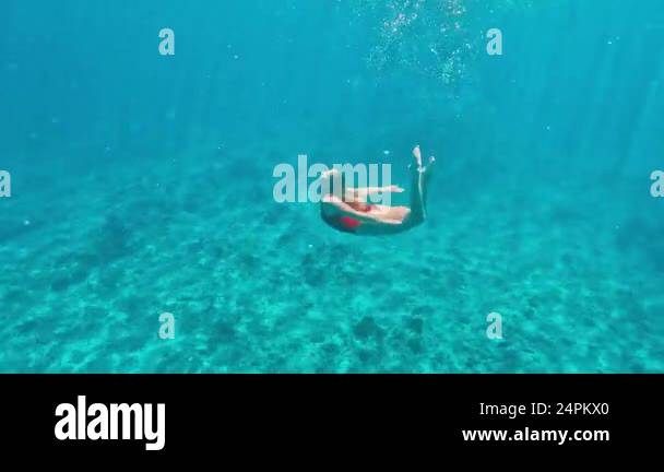 Professional swimmer in a red swimsuit gracefully moves through the ...