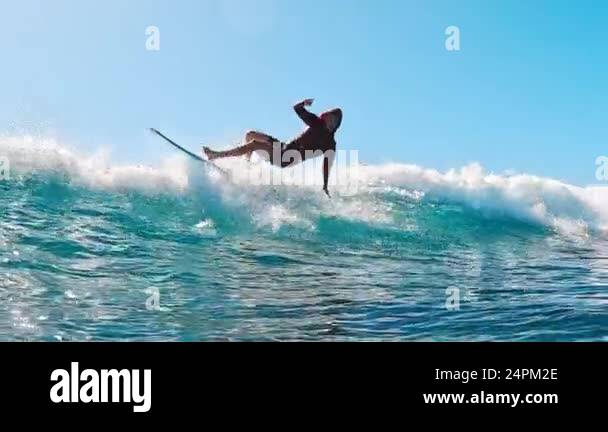Surfer attempts to ride a wave but falls off his board and gets ...