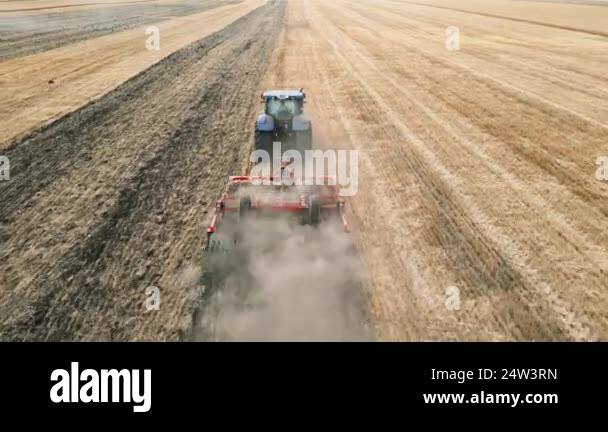 A powerful tractor is plowing the rich, fertile soil in a vast ...