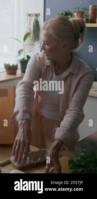 Medium shot of adult Caucasian woman unpacking fresh produce from brown ...