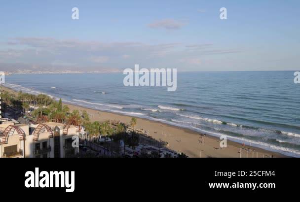 Slow motion aerial footage of the beach front in the Spanish town of ...
