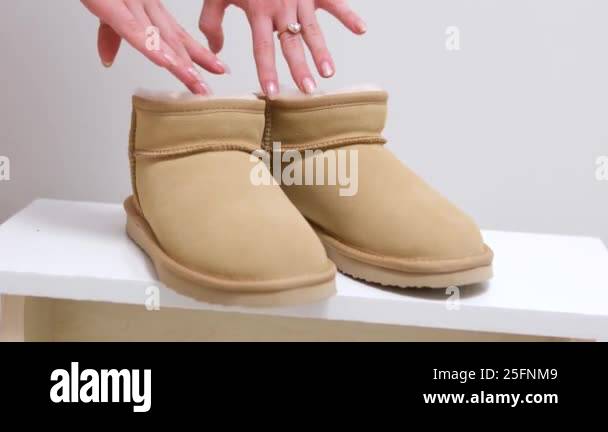 beige uggs girl touches hands examines shoes leg with white sock try on shoes. warm leather ...
