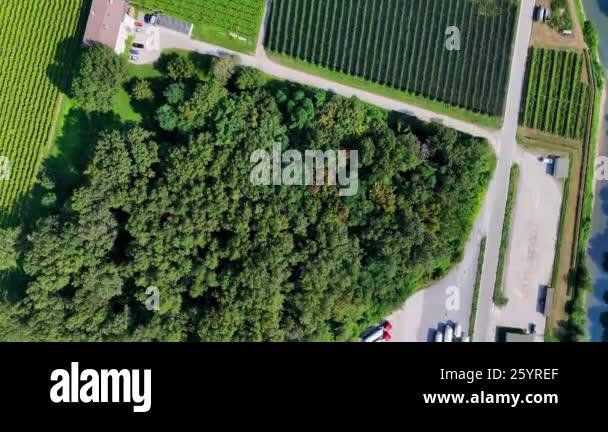 Aerial view camera is panning over a green forest showing a parking lot ...