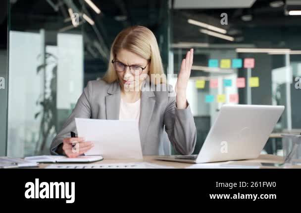 Confused distracted businesswoman having difficulty with paper work in ...