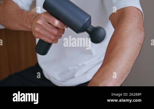 Hands holding massage gun relieving arm muscles pain in apartment ...