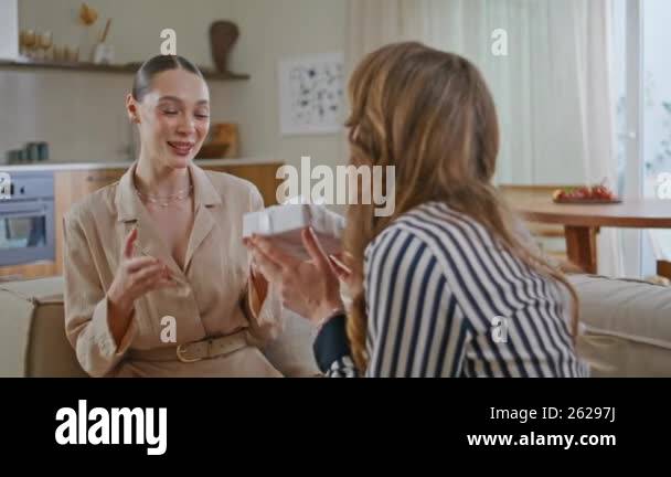 Girl giving present to friend at home birthday celebration closeup ...