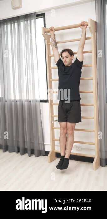 Happy man doing hanging leg raise exercise on wall bars to strengthen ...