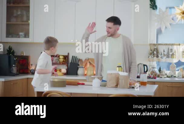 A dad and his son high five in the kitchen, excited to start baking ...