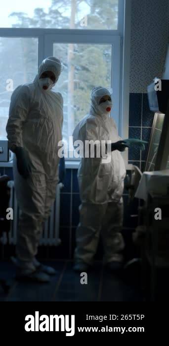 Two scientists in protective suits stand and discuss in a laboratory ...