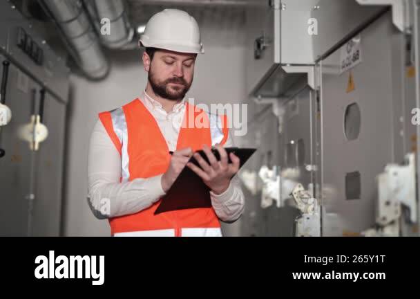 Confident electrical engineer in orange safety vest and white hard hat ...
