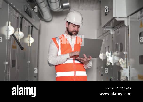 Industrial electrician engineer uses laptop to monitor, maintain and ...