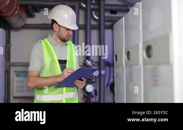 Serious man engineer in boiler room checks heating system equipment ...