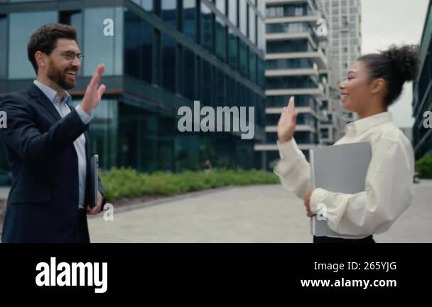 Two multiracial business colleagues meeting in city high five hello hi ...