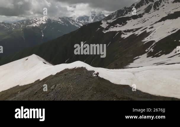 Aerial view of solo hiker man with backpack trekking in high snowy ...