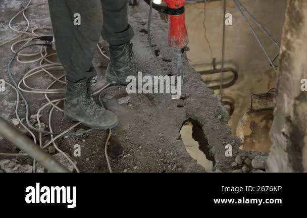 Men in boots break concrete for residential building reconstruction ...