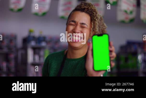 Laughing shopkeeper showcasing a smartphone with a green screen and ...
