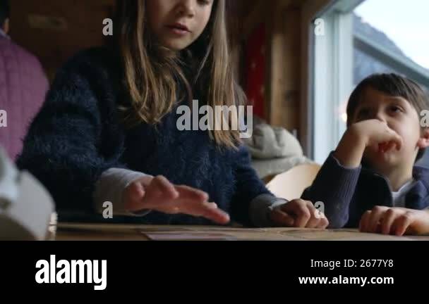 Closeup child hand picking food from restaurant menu, young siblings at ...