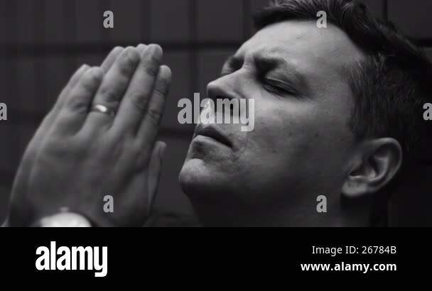 Man praying with hands joined, eyes closed, seeking hope and guidance ...