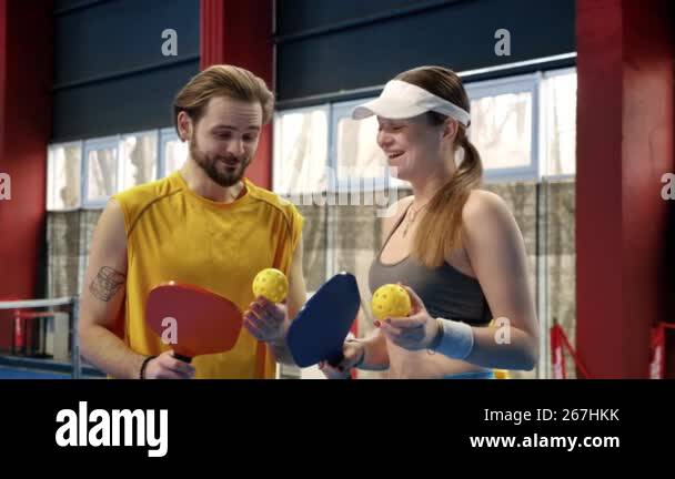 A man and a woman talking and looking at paddles after playing ...