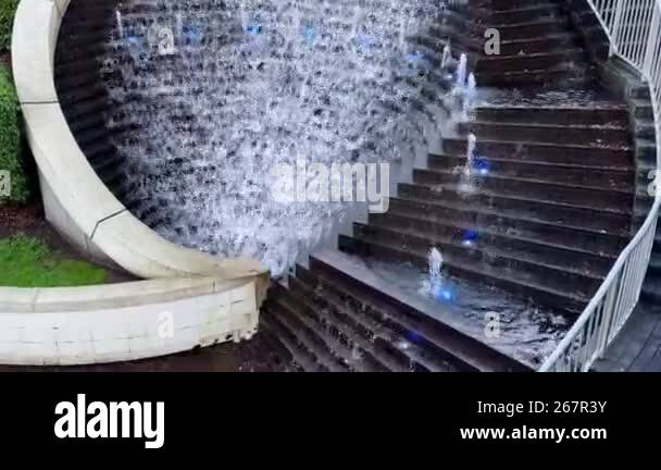 Decorative waterfall with steps and plants in the city center.4k ...