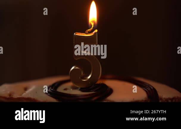 Blowing out candles on a birthday cake with the number 5 .The fire ...