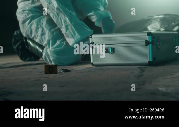 Ground level lowkey shot of forensic expert wearing protective costume ...