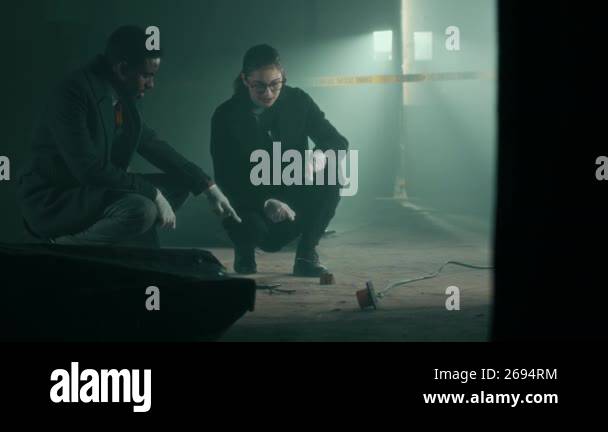 Full low-key shot of young skilled Caucasian female detective and young ...