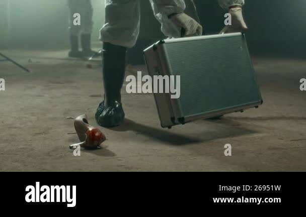 Ground level lowkey shot of forensic expert in protective suit ...