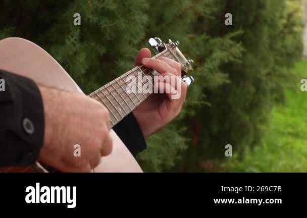 Close up of man's hand clamping a chord on guitar neck. Learning to ...