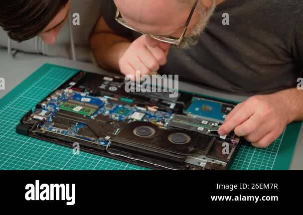 Father with son analyzing laptop components, considering repair options ...