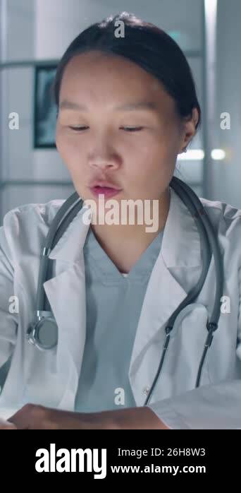 Vertical POV of Asian female pulmonologist in white coat with ...