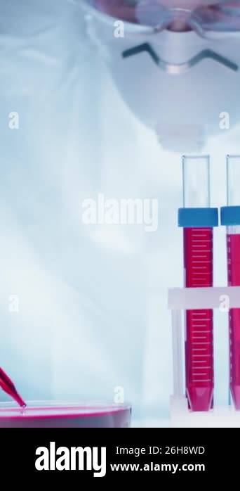 Vertical tilt up view of male chemist in protective suit filling lab ...