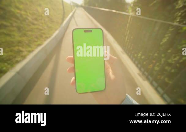 Footage of hand of young man holding smartphone with green screen while ...