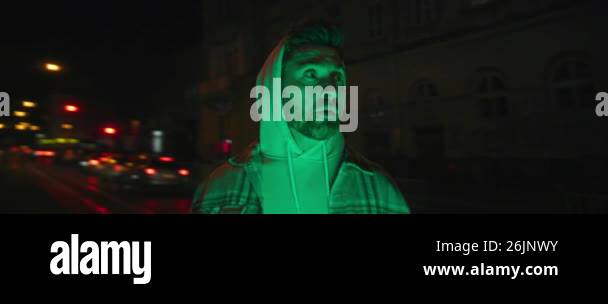 Handsome man walking through night city. Looking around scared serious ...