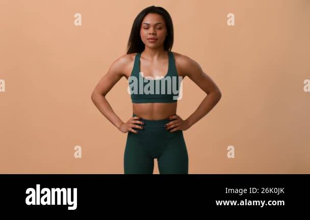 A young African American woman stands confidently with hands on hips, displaying her athletic ...