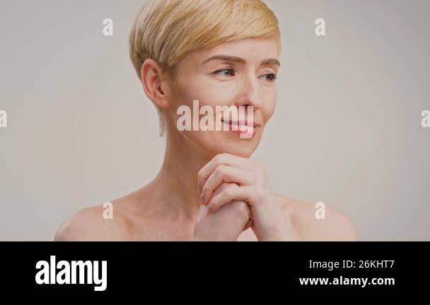 A Caucasian woman in her 50s is applying skincare products on her face ...