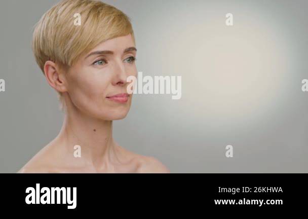 A Caucasian woman in her 50s is applying skincare products on her face ...