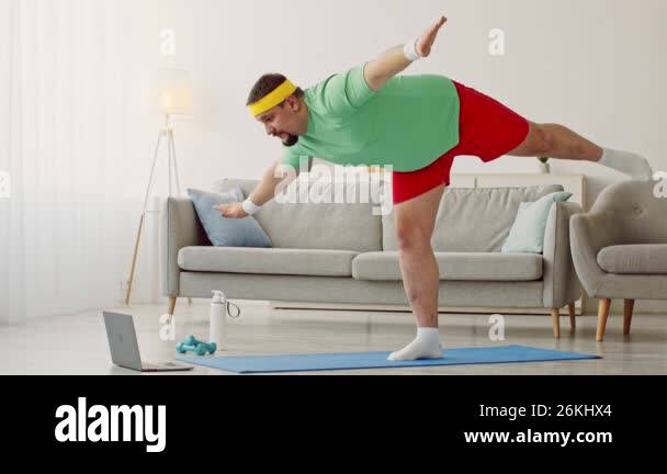 A millennial man with a chubby build engages in a home workout routine ...