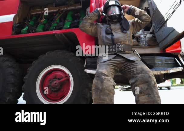 Young tired fireman removing full equipment from himself after ...