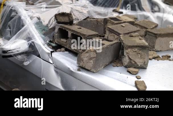 Construction debris falls on a parked car during a storm in an urban ...