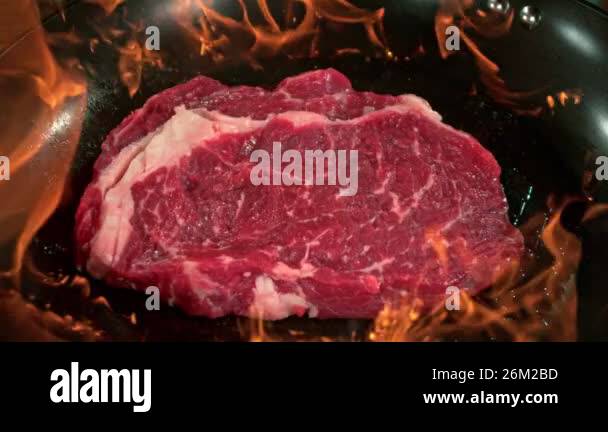 Super Slow Motion Shot of Raw Beef Steak Throwed into Fired up Pan with ...